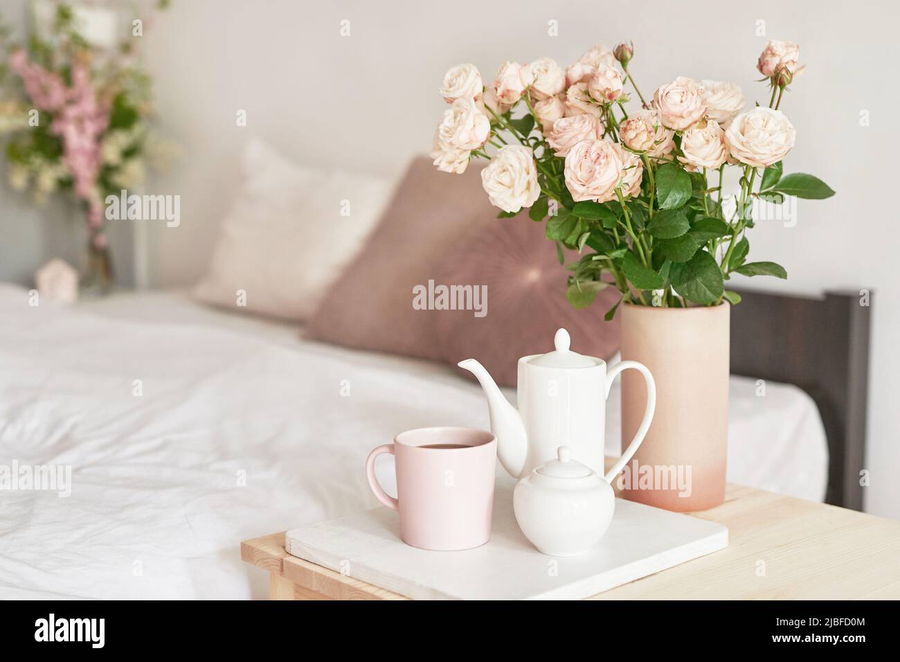 Good cozy morning. Bouquet of rose flowers in vase on table. Hotel room ...