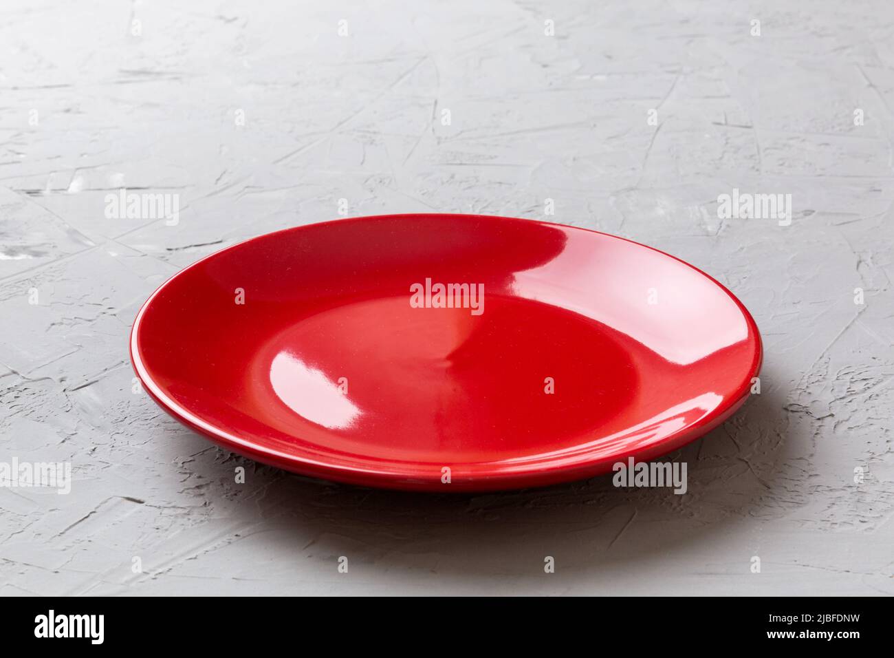 Perspective view of empty red plate on cement background. Empty space ...