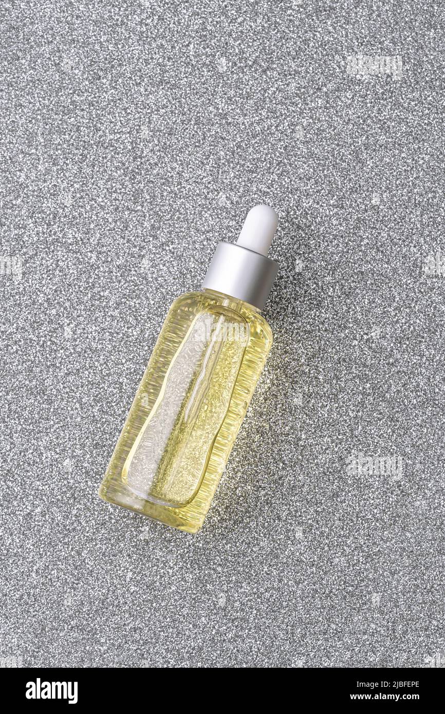 Yellow vitamin C yellow serum in transparent bottle on sparkling silver ...