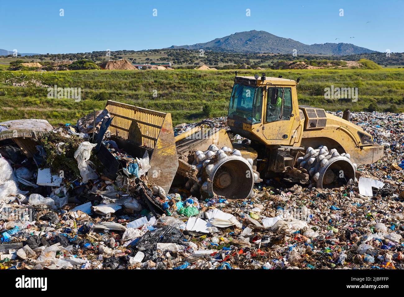 Heavy machinery shredding garbage in an open air landfill. Waste Stock ...