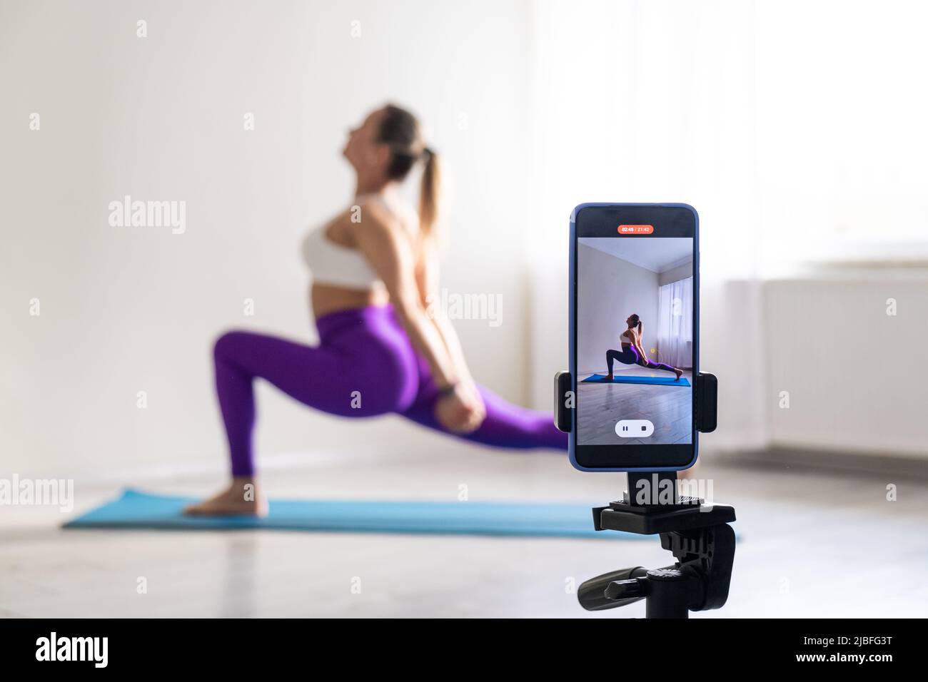 woman practicing yoga poses stretching in front of phone camera sport ...