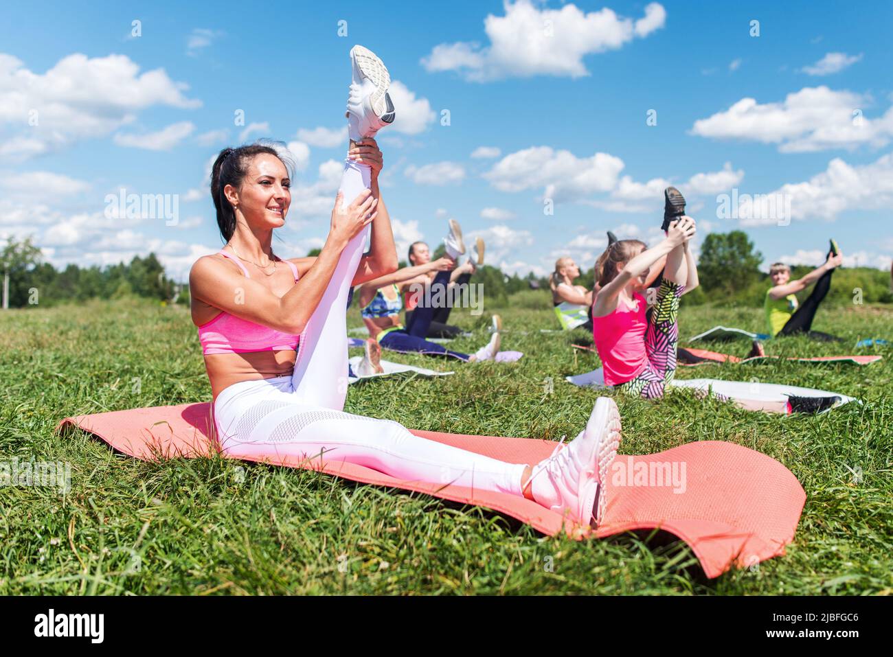 Fit women doing exercises stretching hamstrings lifting legs fitness ...