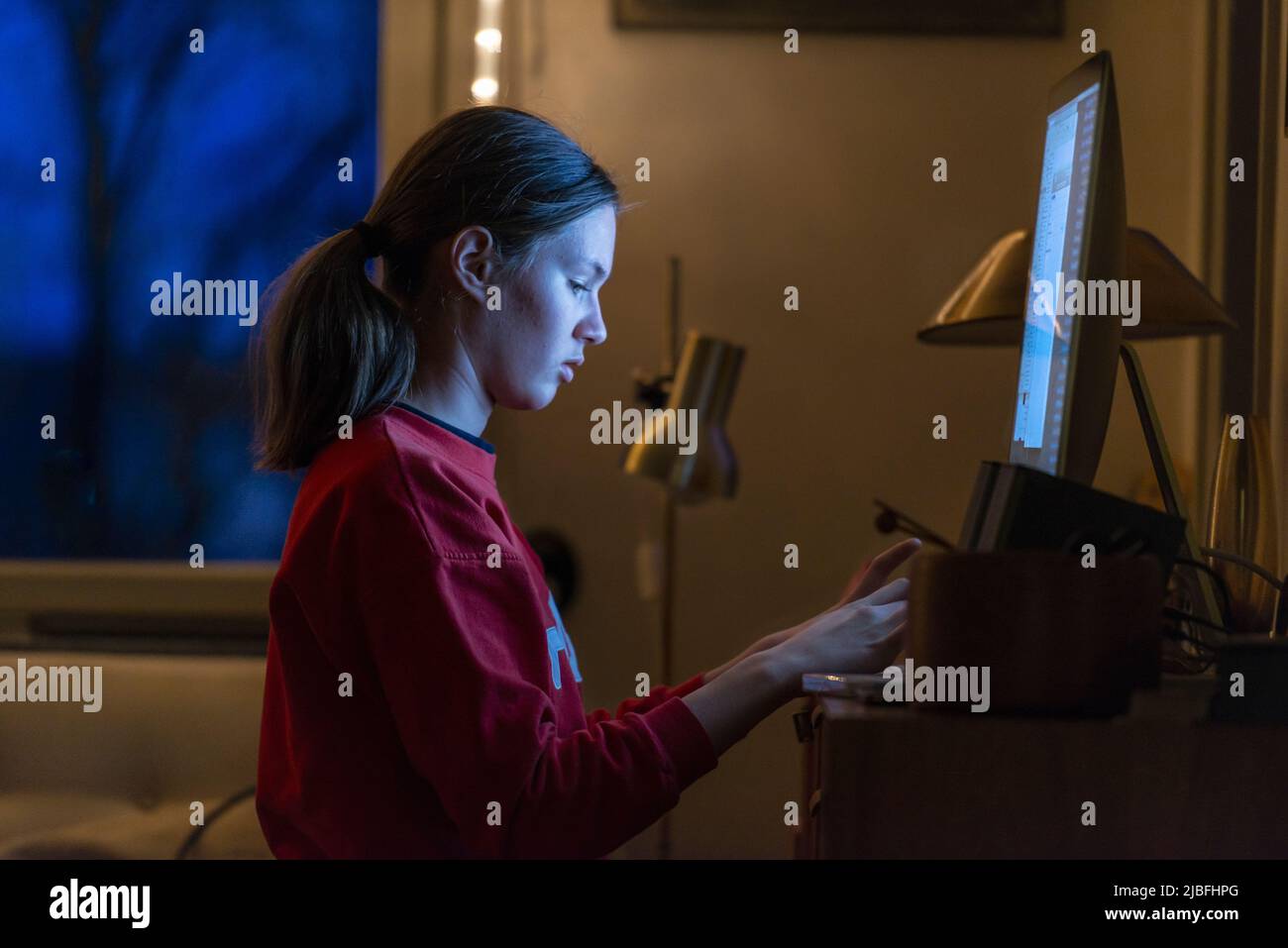Teenage girl using computer at night Stock Photo - Alamy