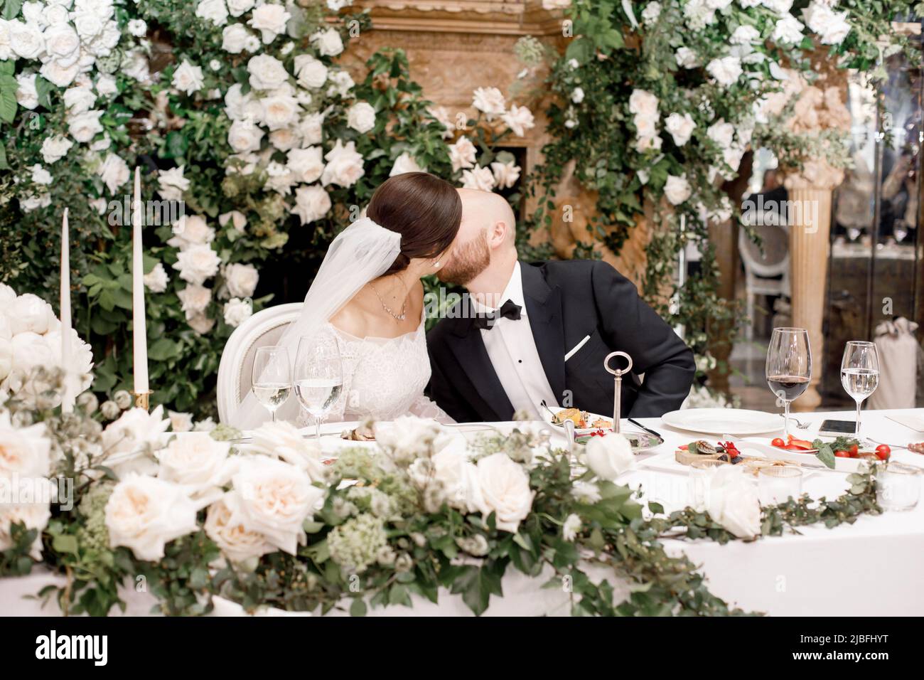 Bride and groom kissing at the wedding table Stock Photo - Alamy
