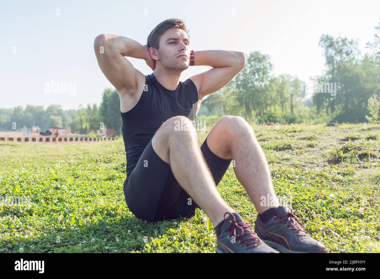 Fitness training. Young sportsman doing abdominal crunches outdoors ...