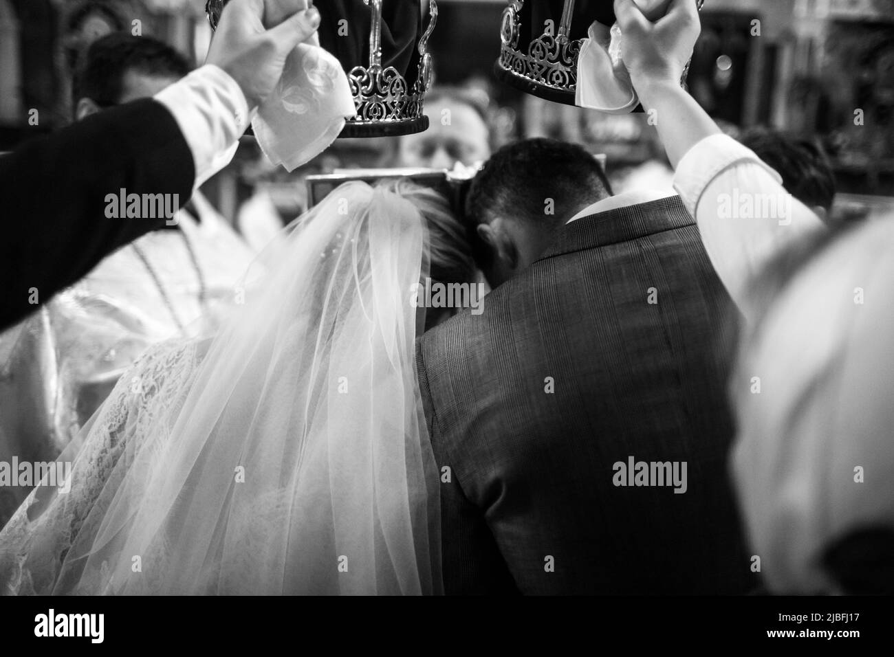 Witnesses of the bride and groom hold crowns at a ceremony in the ...