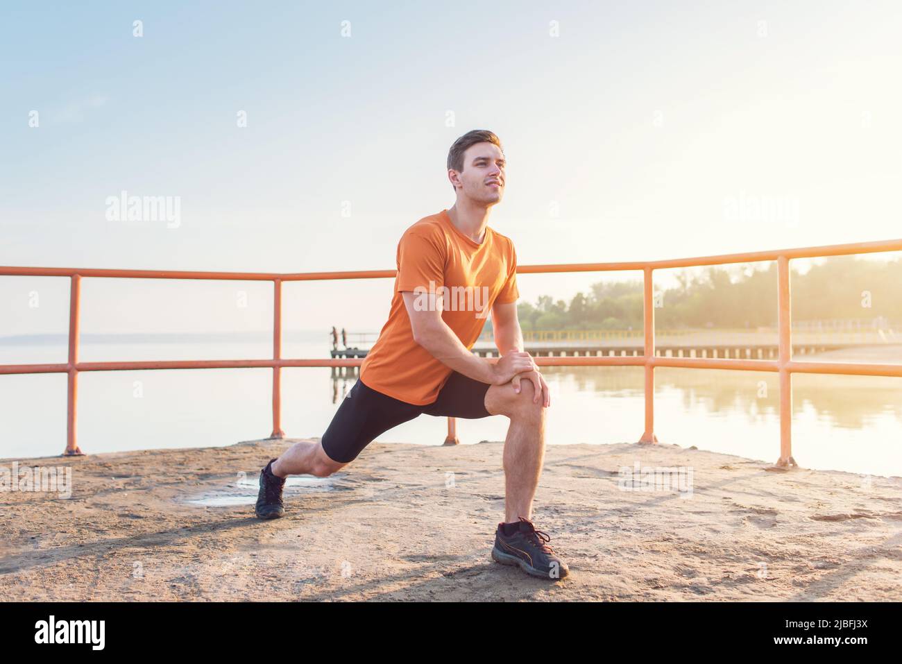 Young fit man stretching legs outdoors doing forward lunge Stock Photo ...