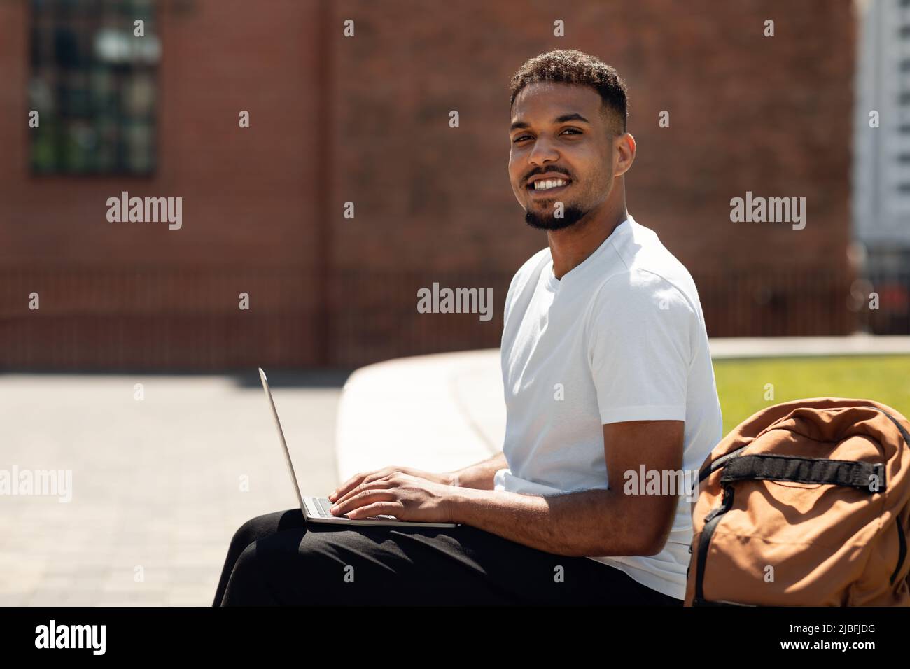 Happy black student guy with laptop computer doing homework, sitting ...