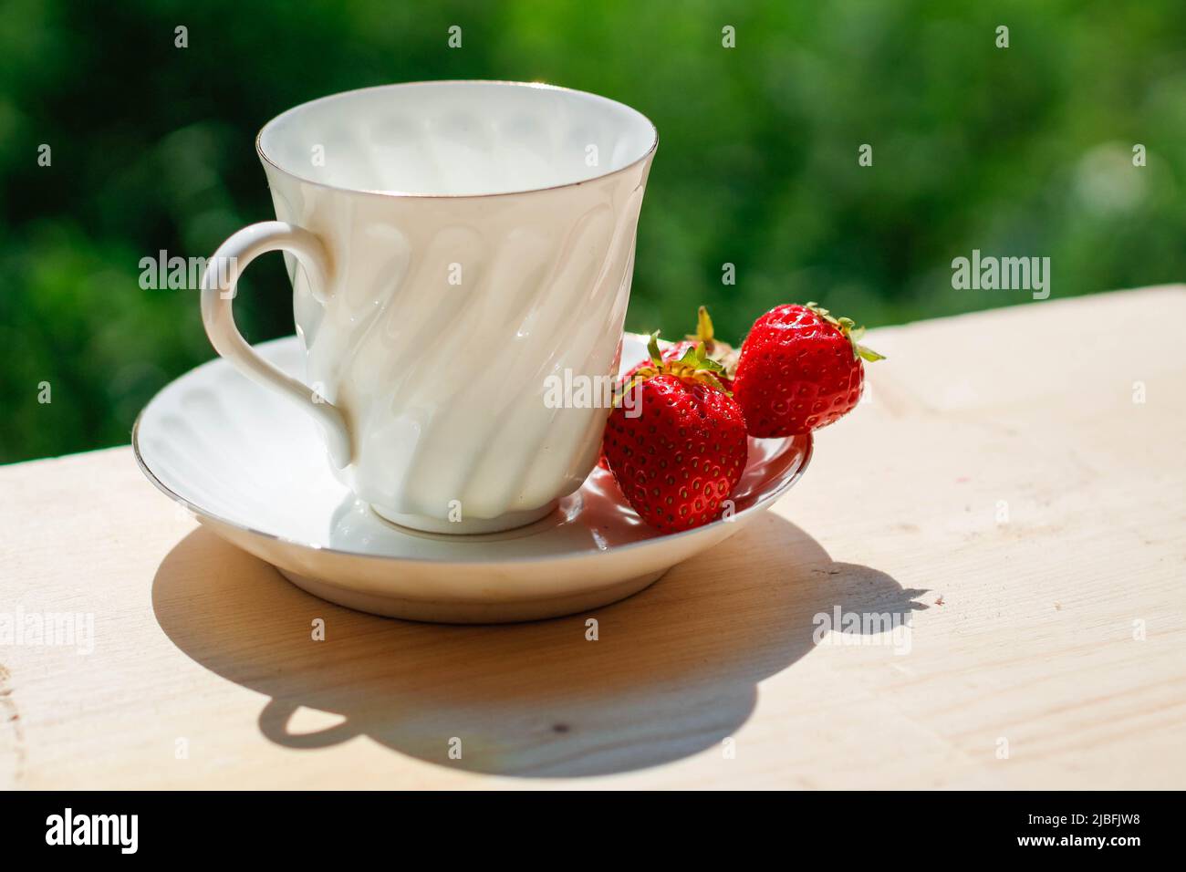 Elegant white porcelain Cup with a Saucer and Strawberries on a wooden ...