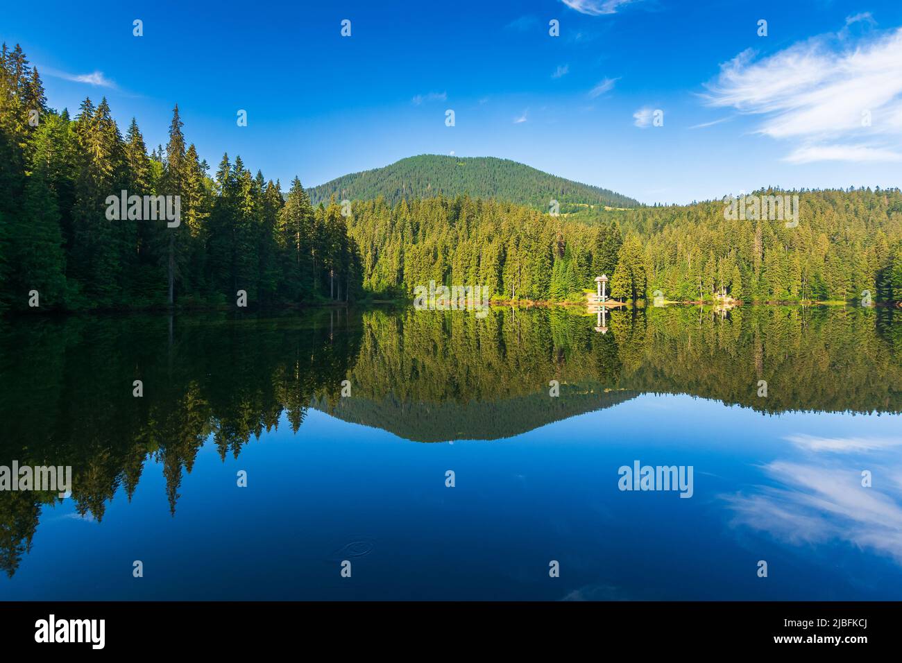 outdoor scene with calm lake in summer season. green forest reflection in the water. serene ...