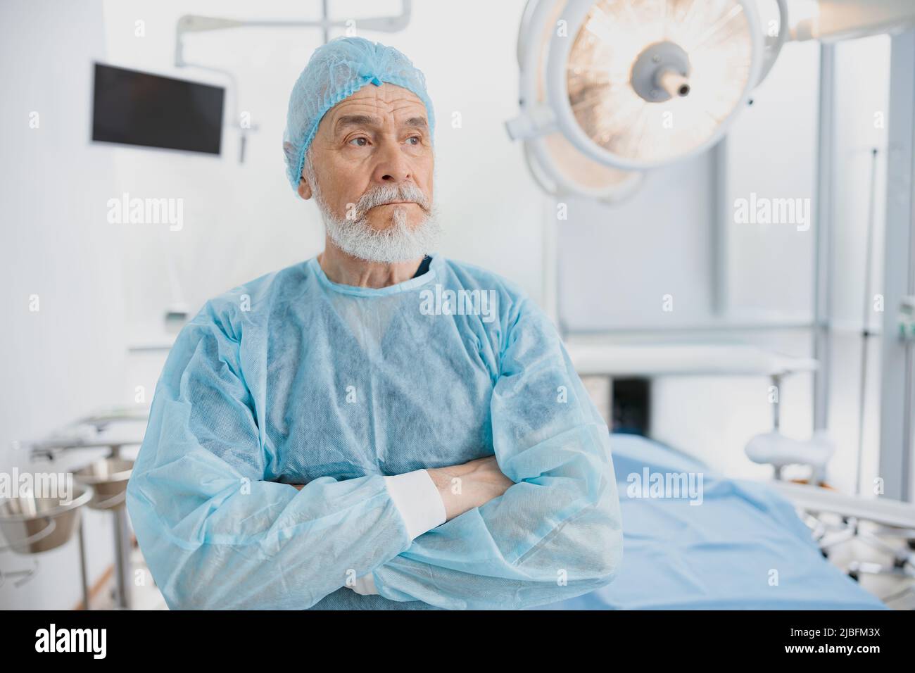 Senior surgeon standing in operating room with crossing hands, ready to ...