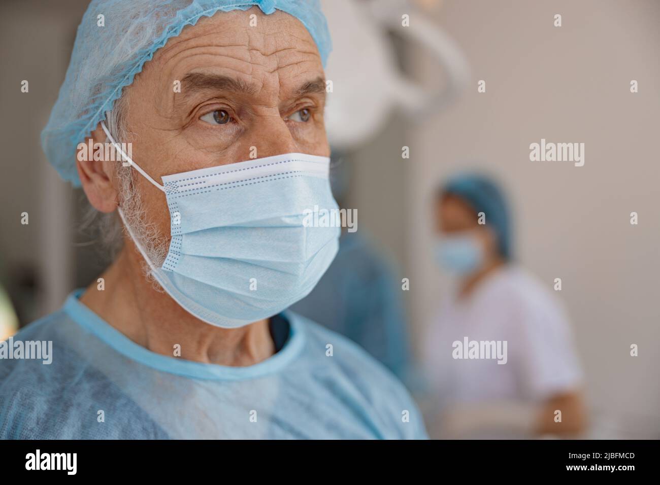 Close up of surgeon in mask standing in operating room, ready to work ...