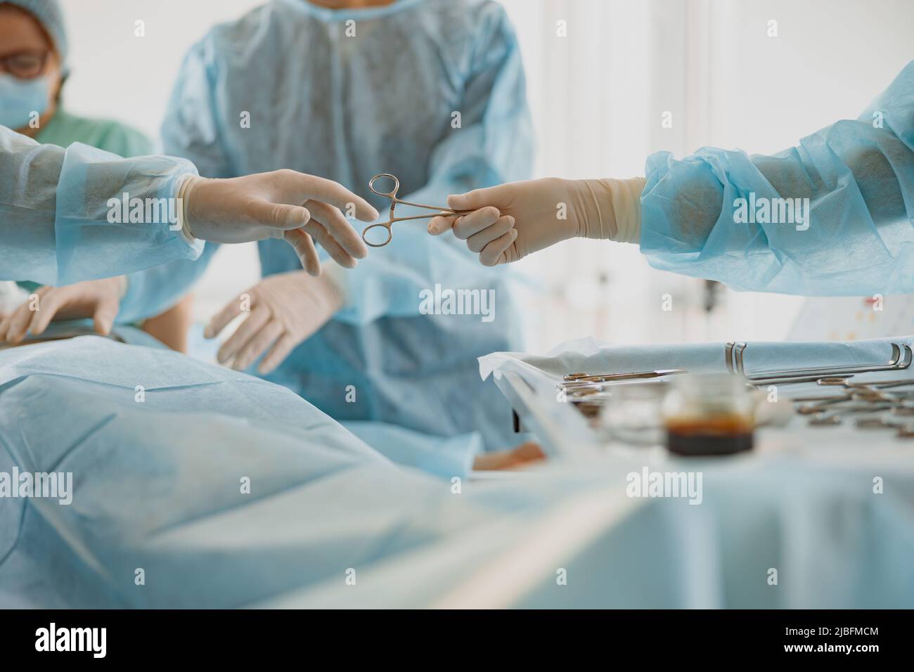 Operating nurse gives clamp to surgeon, the styryl space is needed by ...