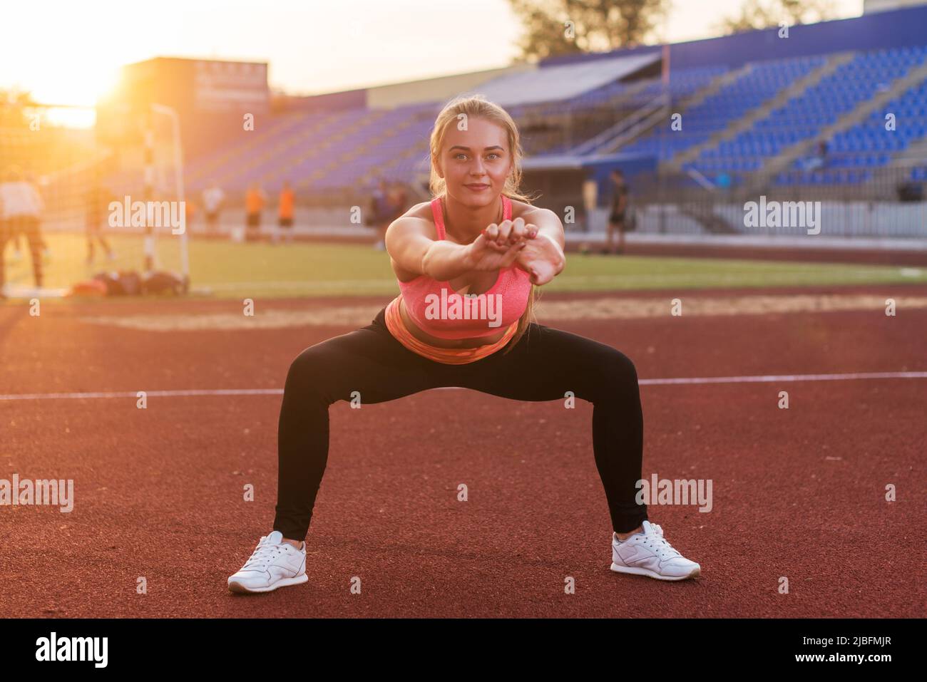 Fitness woman doing squat exercising at stadium. Training outdoors ...