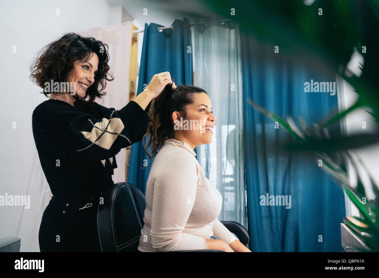 Side view of positive hairdresser in casual clothes smiling and ...