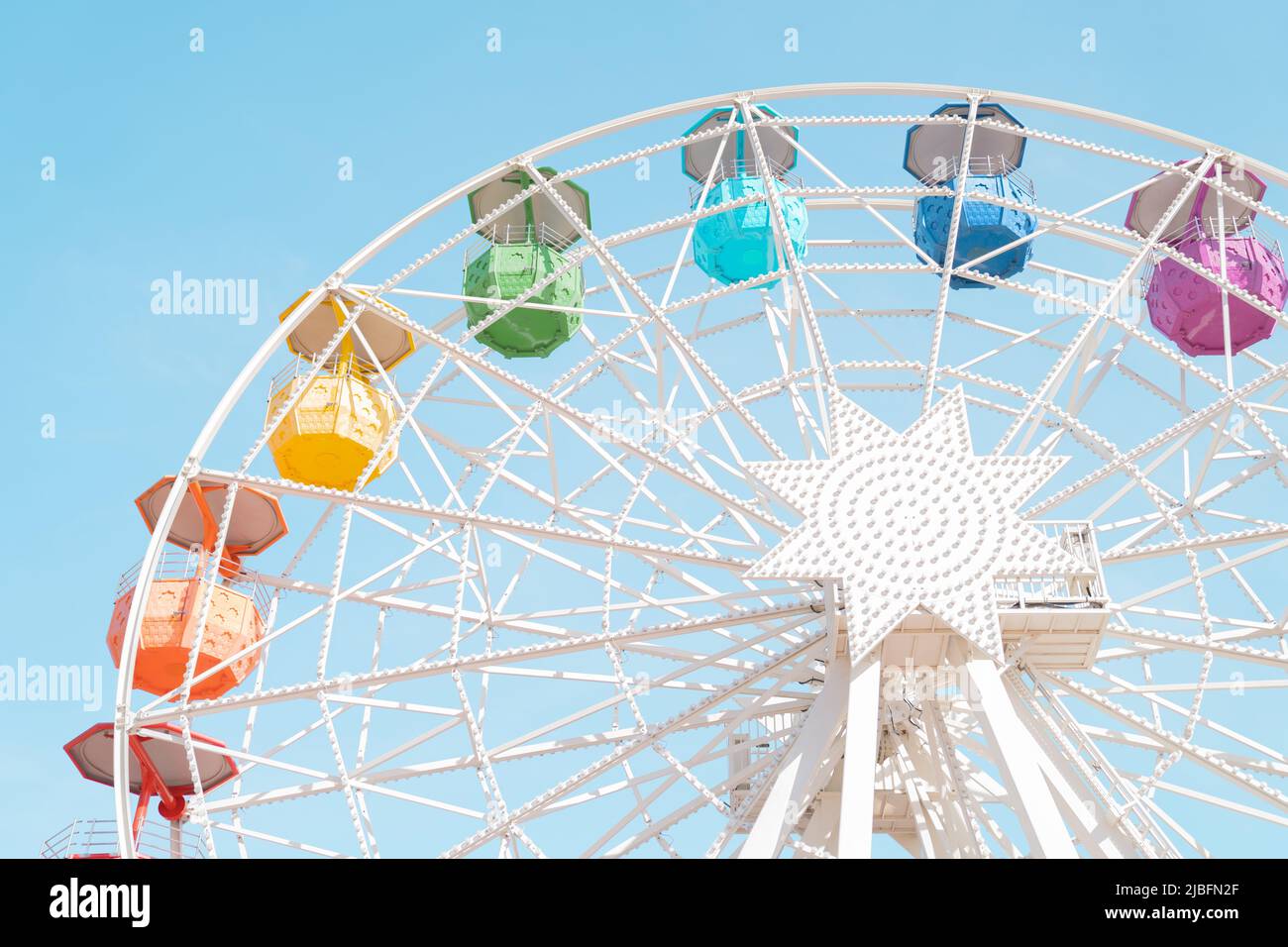 From below white Ferris wheel with colorful carts located against ...