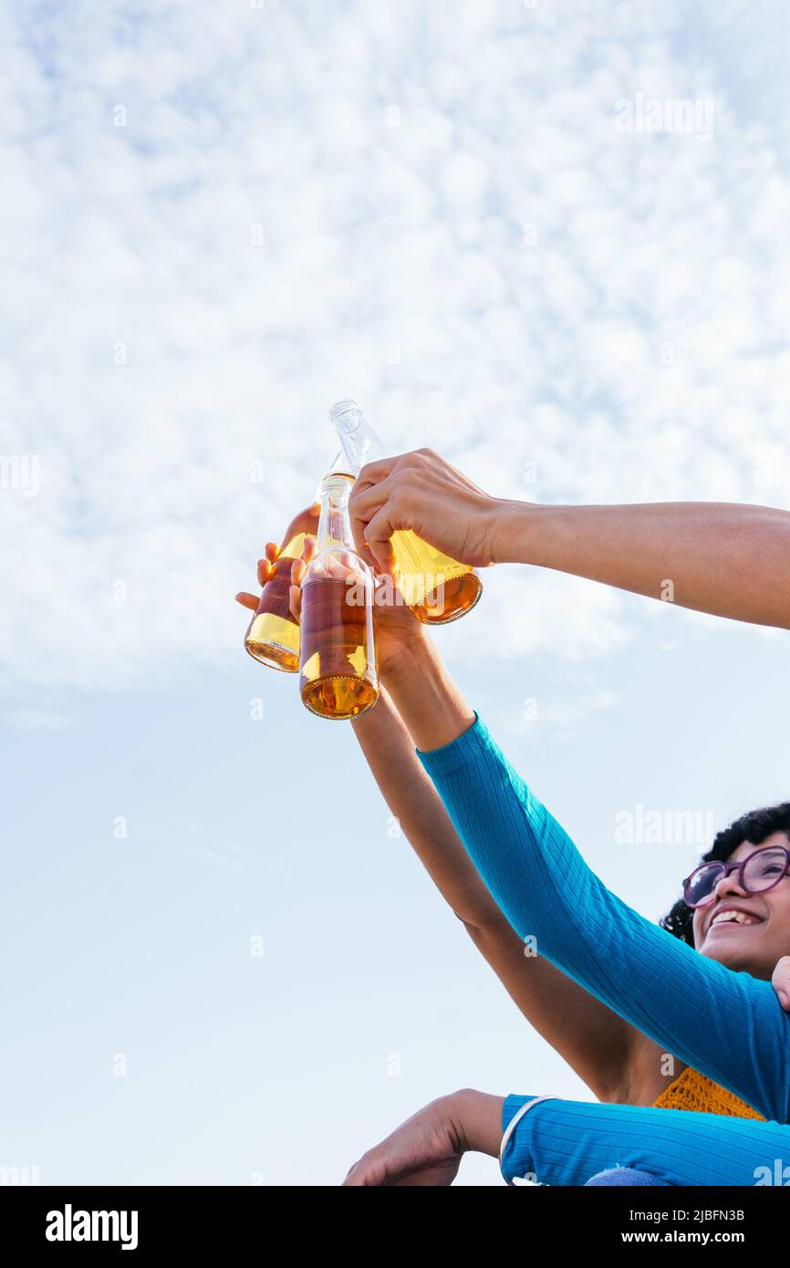 From below anonymous cropped hands of man and women raising bottles of ...