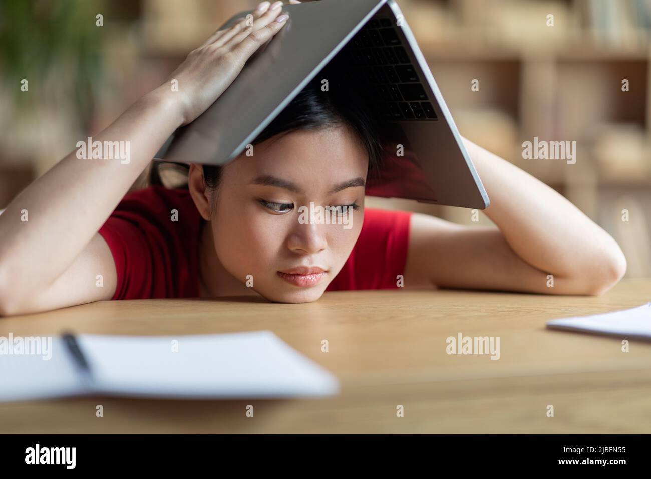 Tired Frustrated Teen Asian Girl Makes Roof With Book On Her Head In