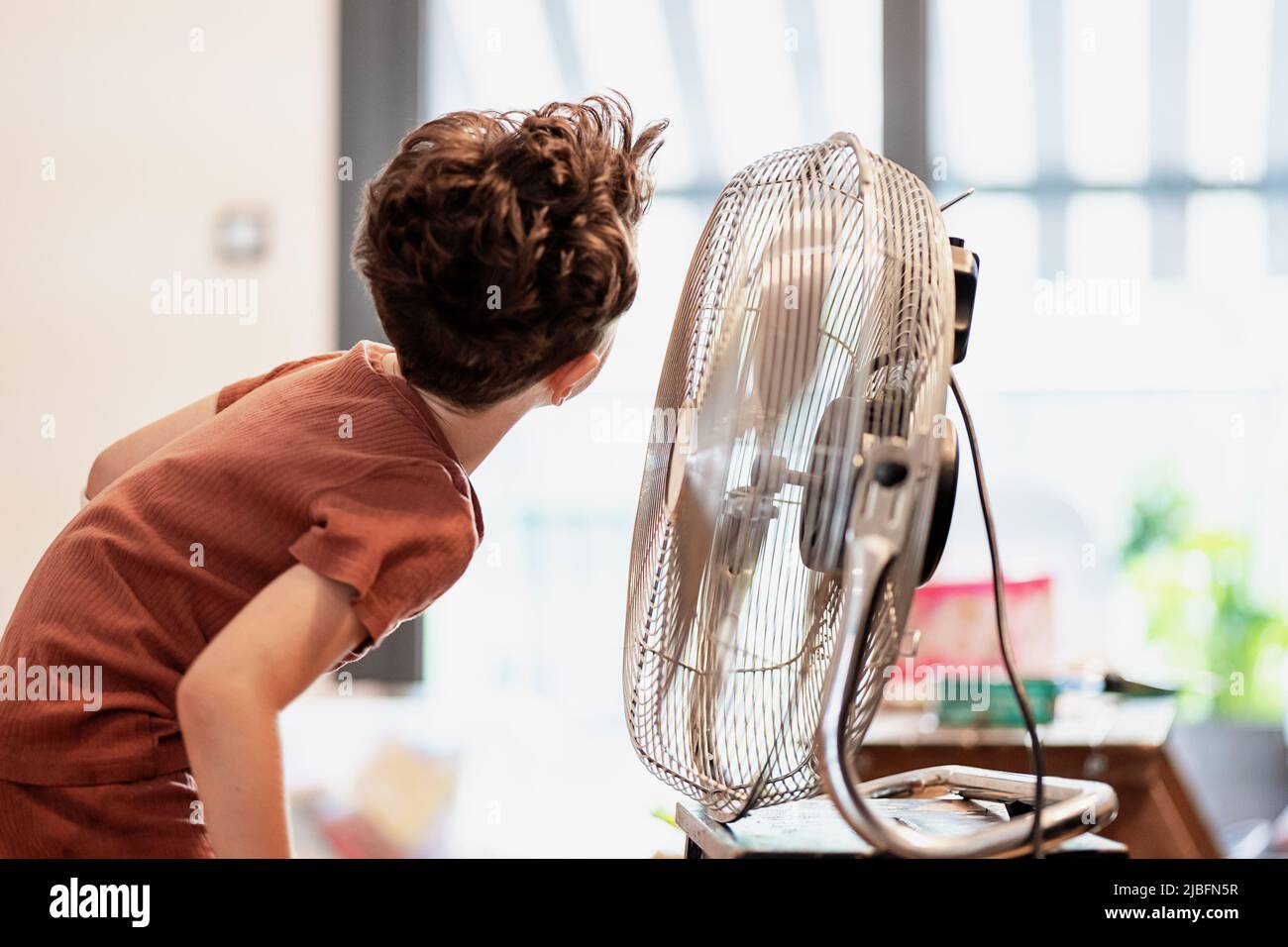 Side view of excited little boy at home playing with fan Stock Photo ...