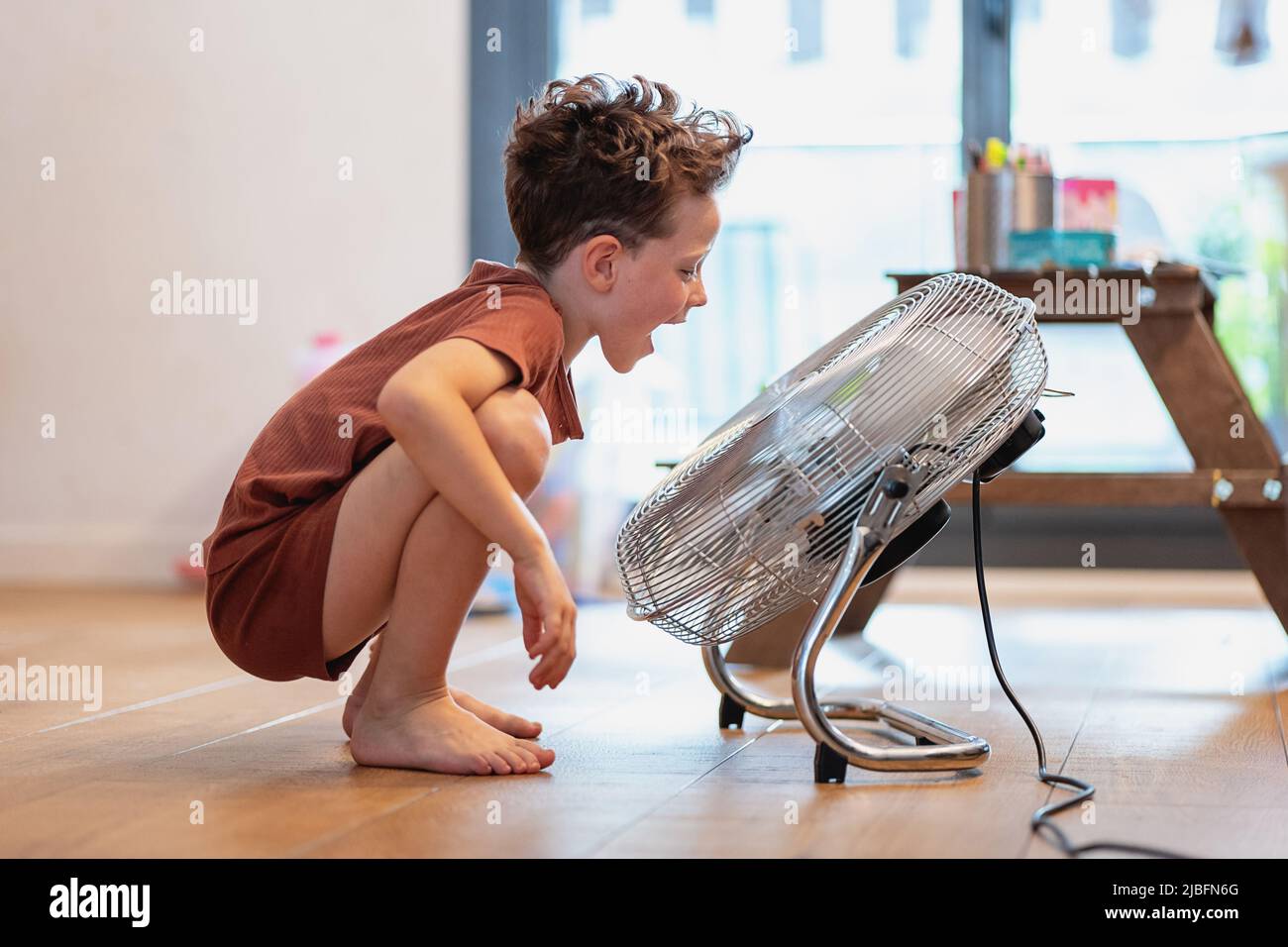 Side view of excited little boy with mouth open at home playing with ...