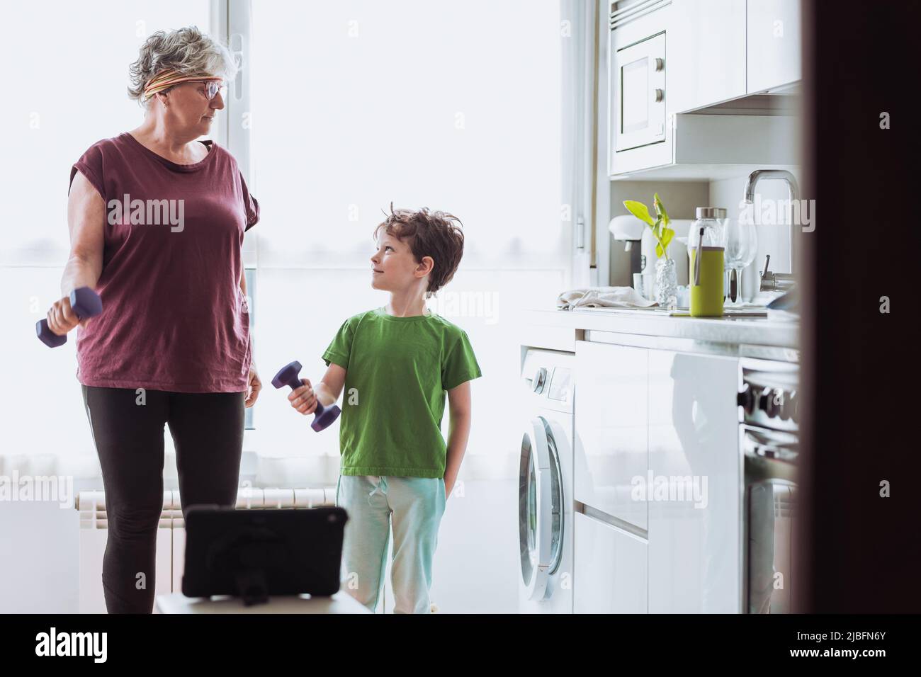 Grandma and grandchild in activewear doing exercise with dumbbells ...