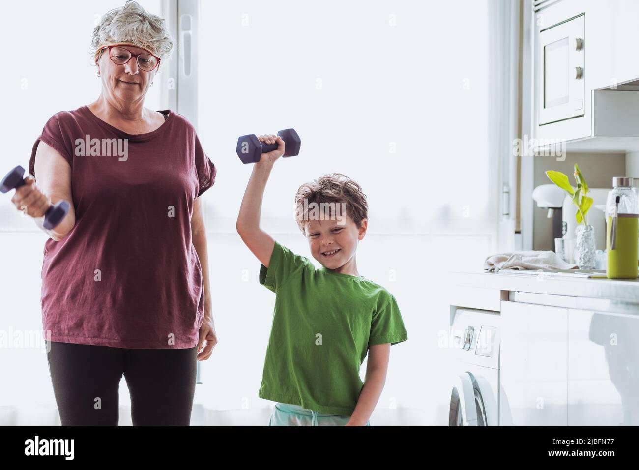 Grandma and grandchild in activewear doing exercise with dumbbells ...