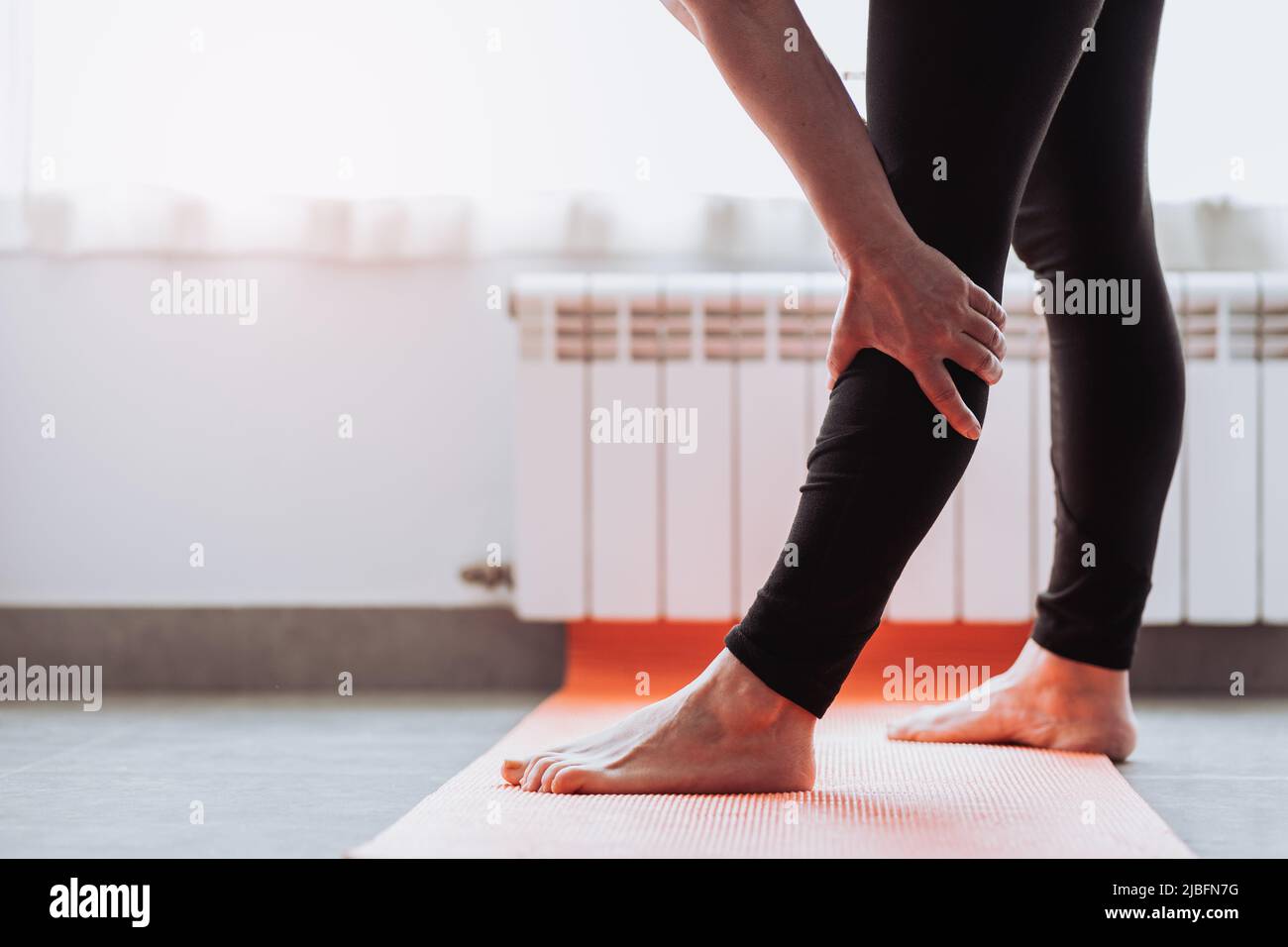 Anonymous barefoot Woman in leggings touching leg and bending forward ...
