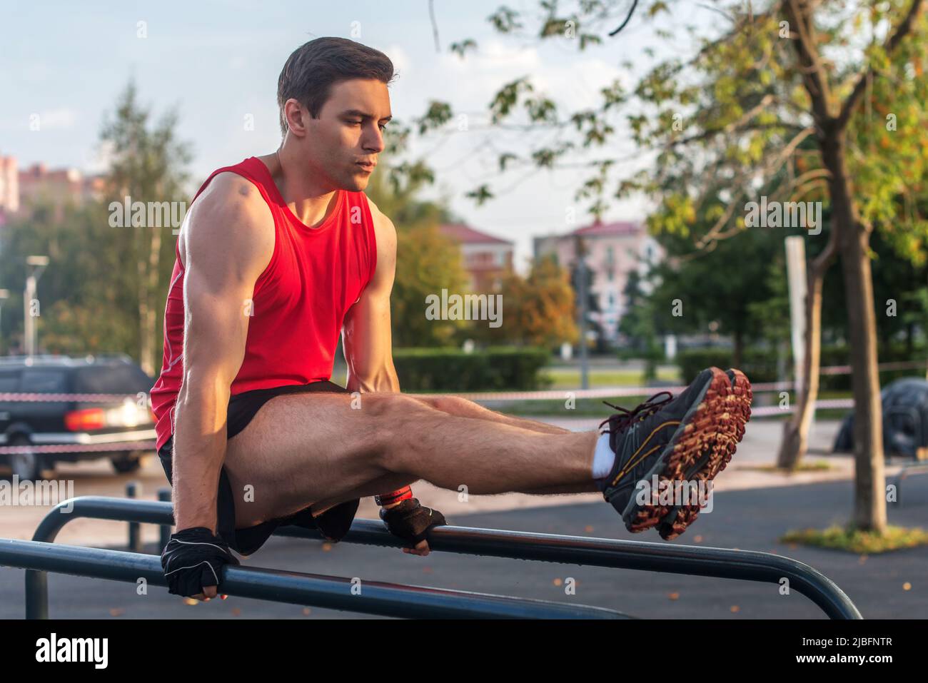 Fit man doing abdominal exercise on parallel bars in summer park Stock ...