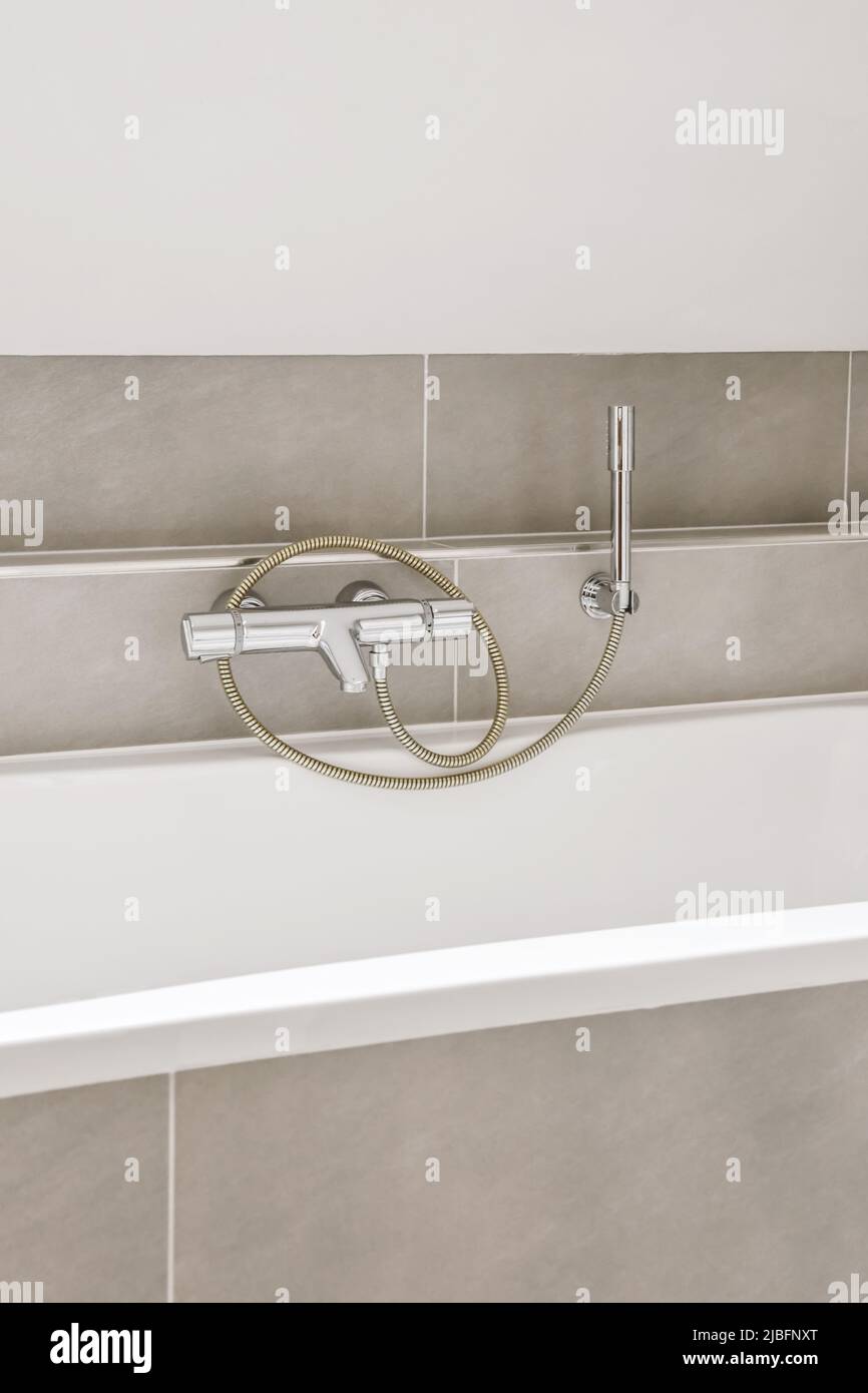 Chrome faucet and small handheld shower head attached to gray tiled ...