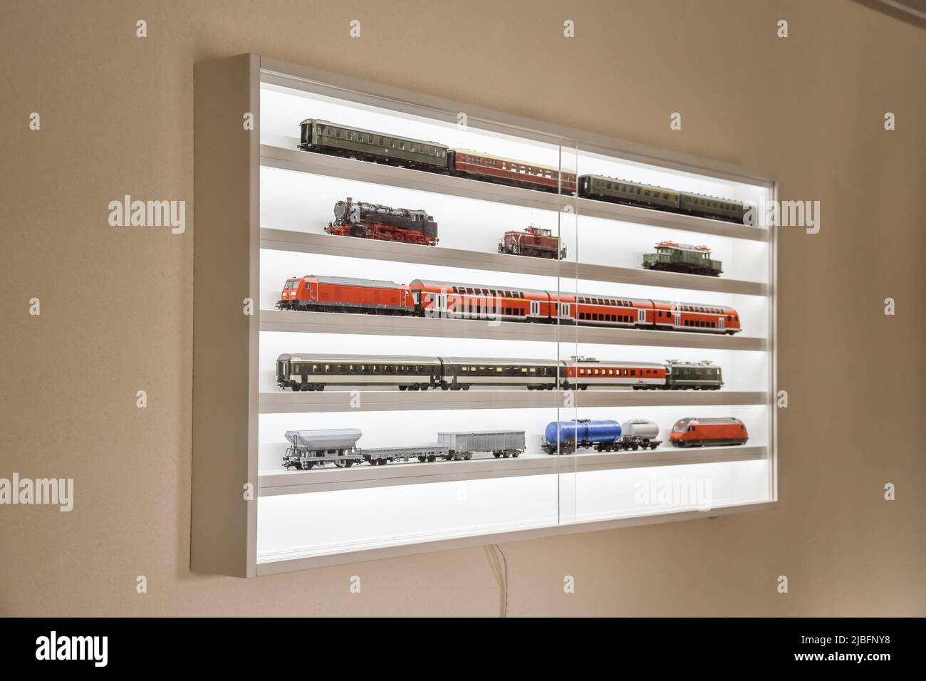 Collection of various modern and retro toy trains placed behind glass ...