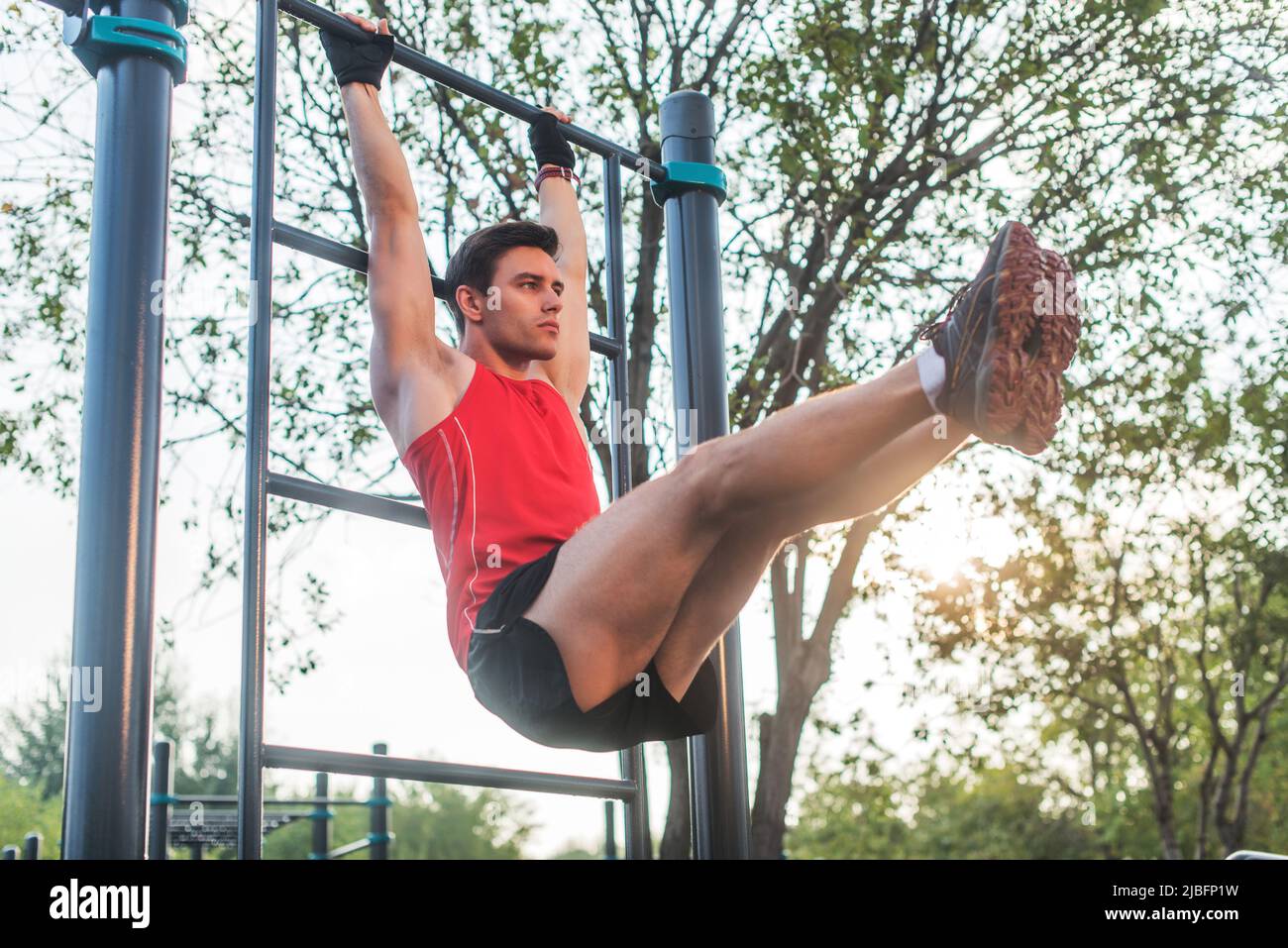 Fitnes man hanging on wall bars performing legs raises. Core cross ...