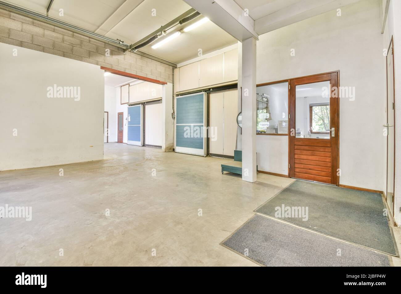 Interior of spacious hallway of modern warehouse with blue slider doors ...