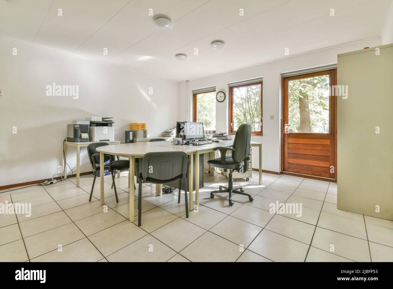 Chairs at oval table with modern computers in spacious office with ...