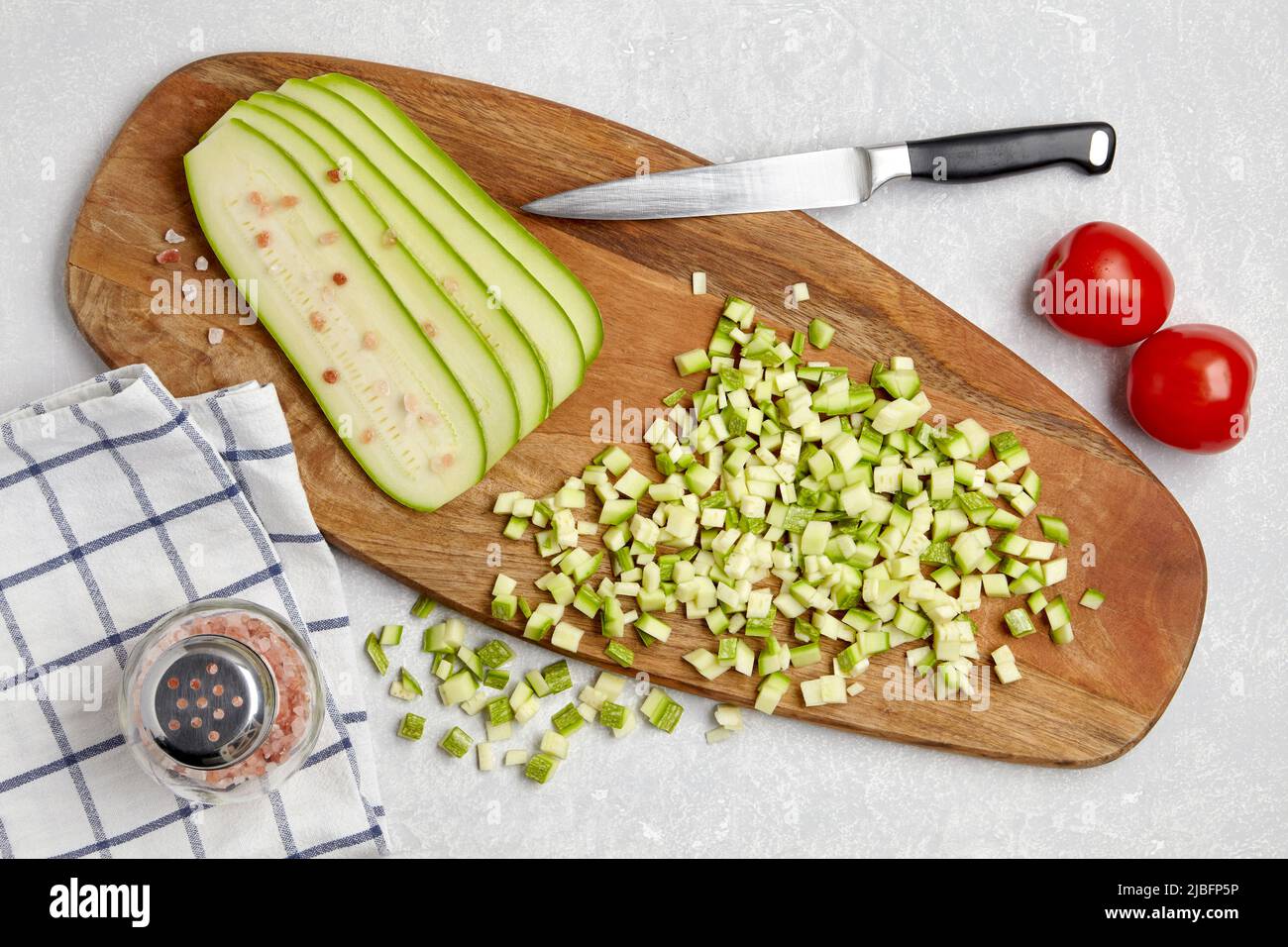 Courgette zucchini diced sliced on a wooden cutting board, tomatoes ...