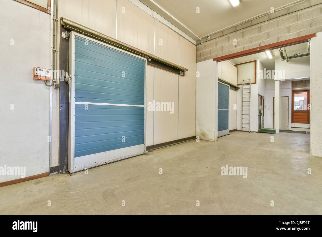 Interior of spacious hallway of modern warehouse with blue slider doors ...