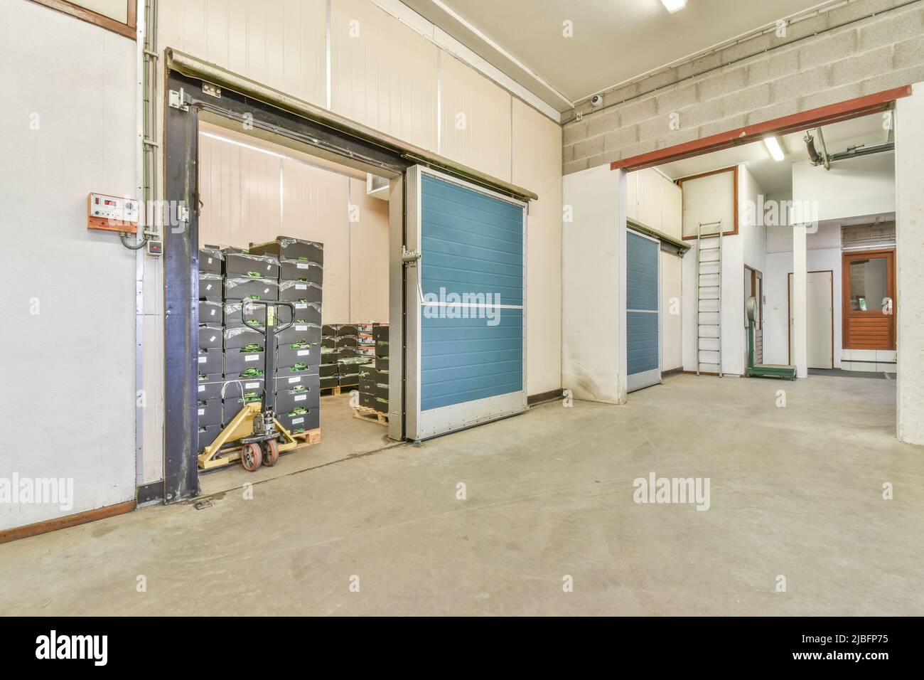 Interior of spacious hallway of modern warehouse with blue slider doors ...