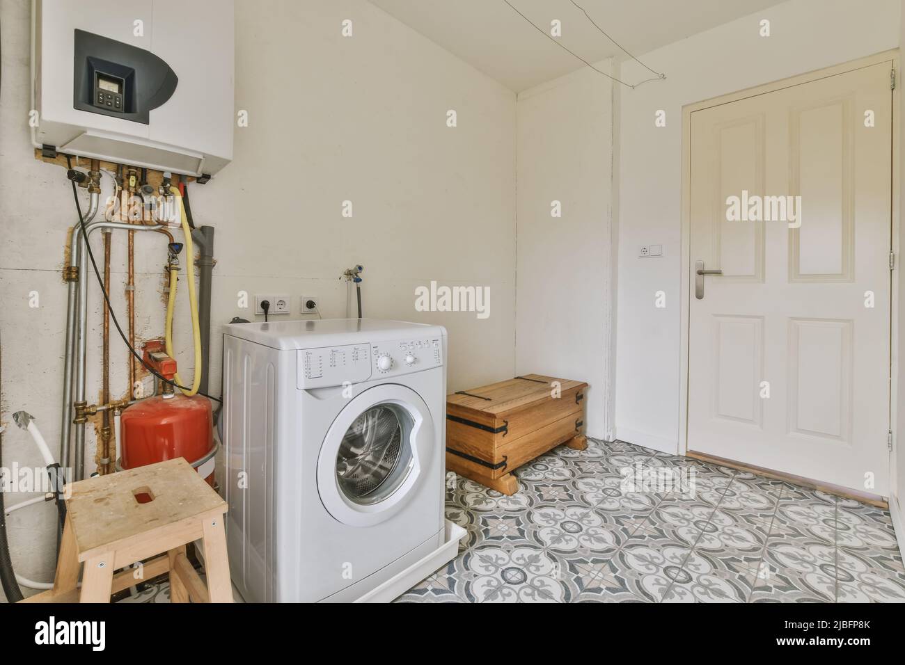 Electric water heater hanging on wall over washing machine near wooden ...