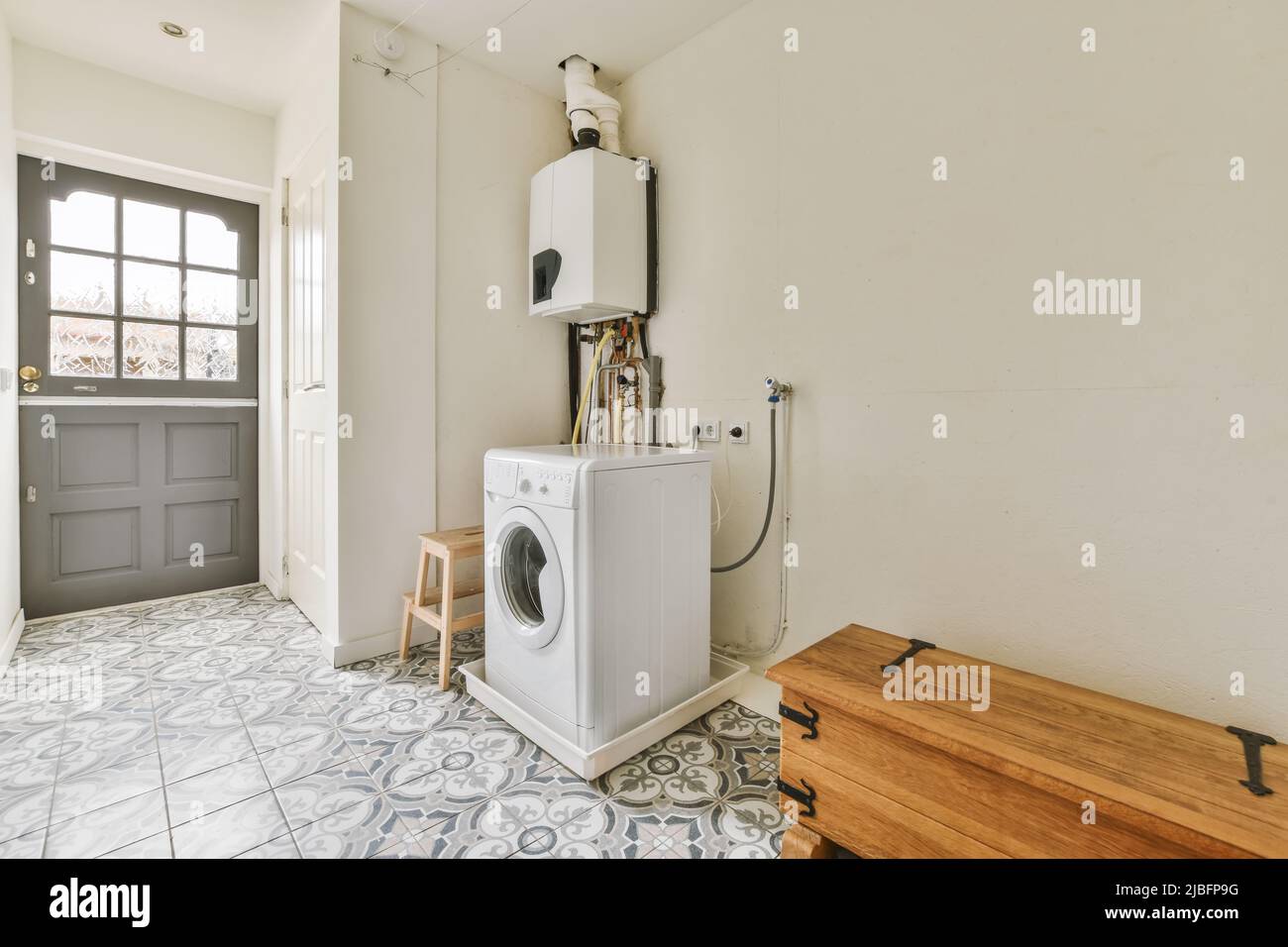 Electric water heater hanging on wall over washing machine near wooden ...