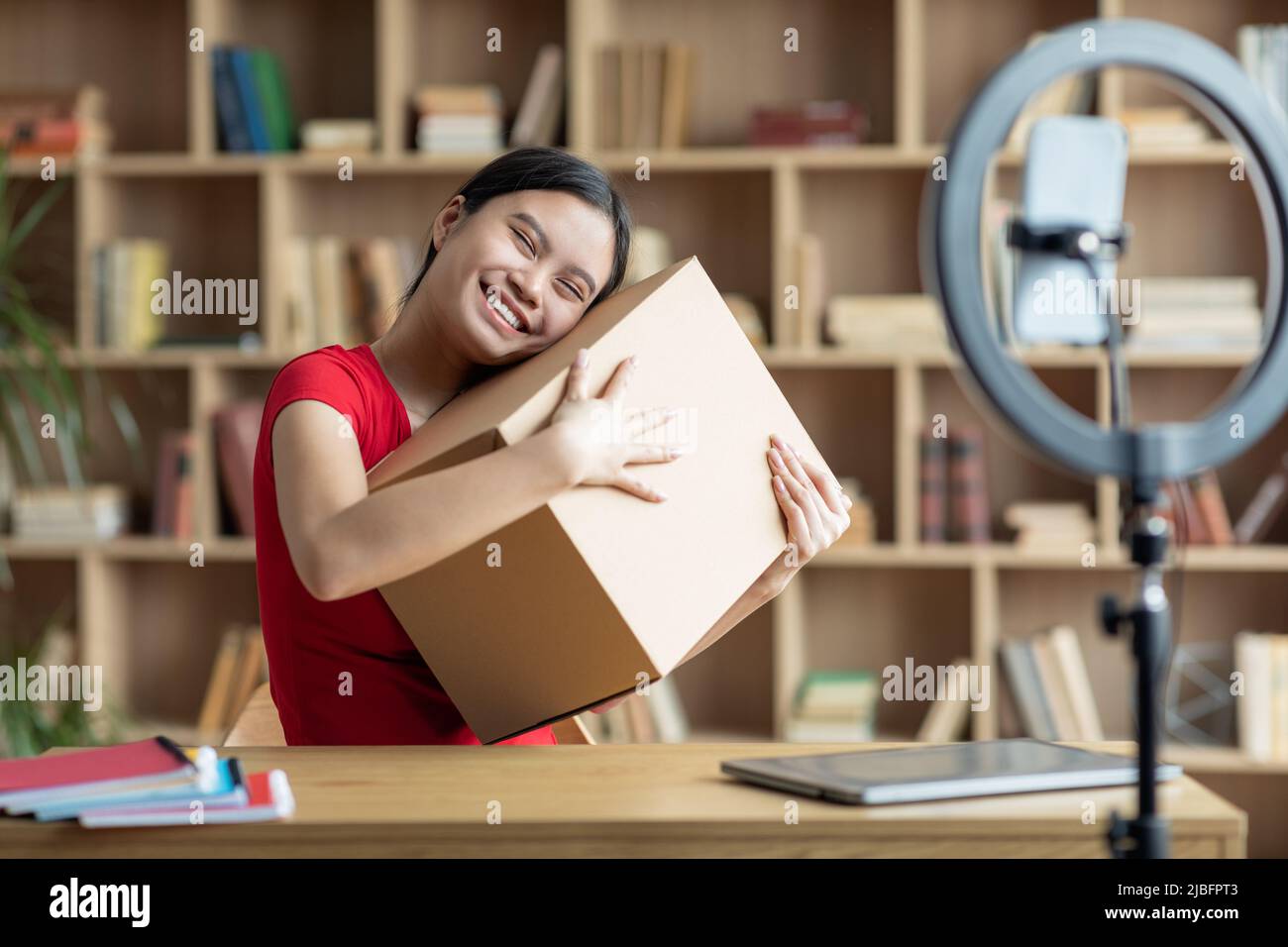 Satisfied teenager japanese lady hugging cardboard box and shooting ...