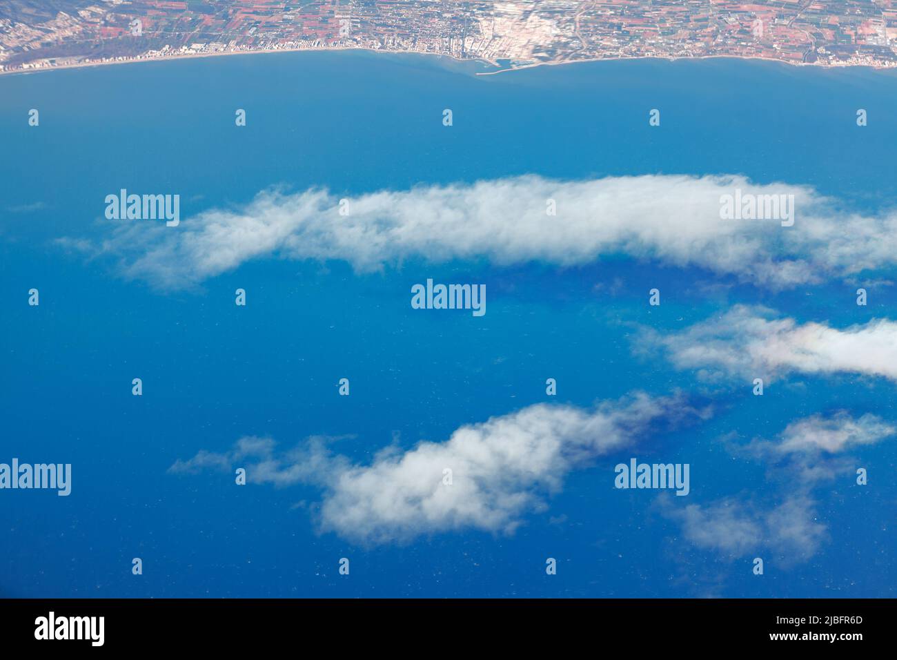 Flight over the ocean and continent . Aerial view of clouds and coast ...
