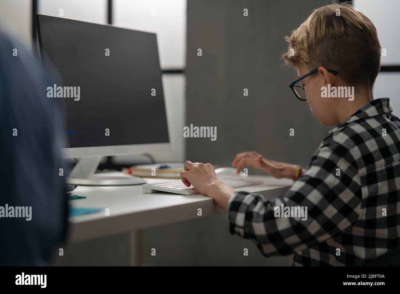 A rear view ofschoolboy using computer in classroom at school Stock ...