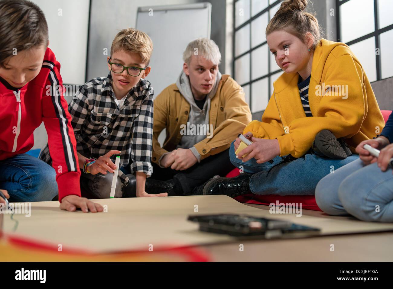 A group of happy kids with their teacher working on project together at ...