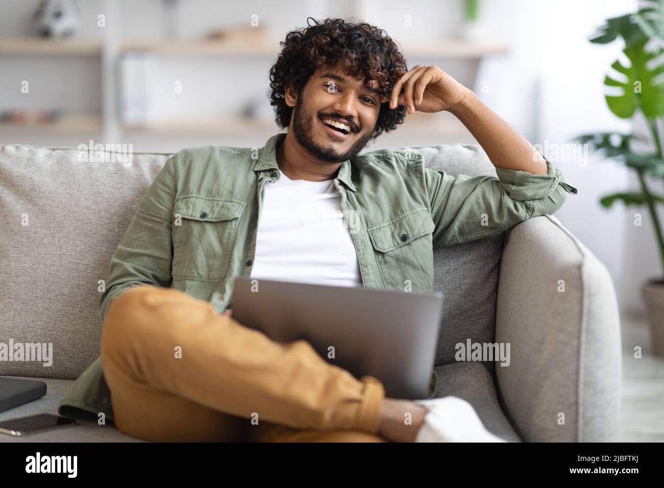 Happy indian guy using notebook at home Stock Photo - Alamy