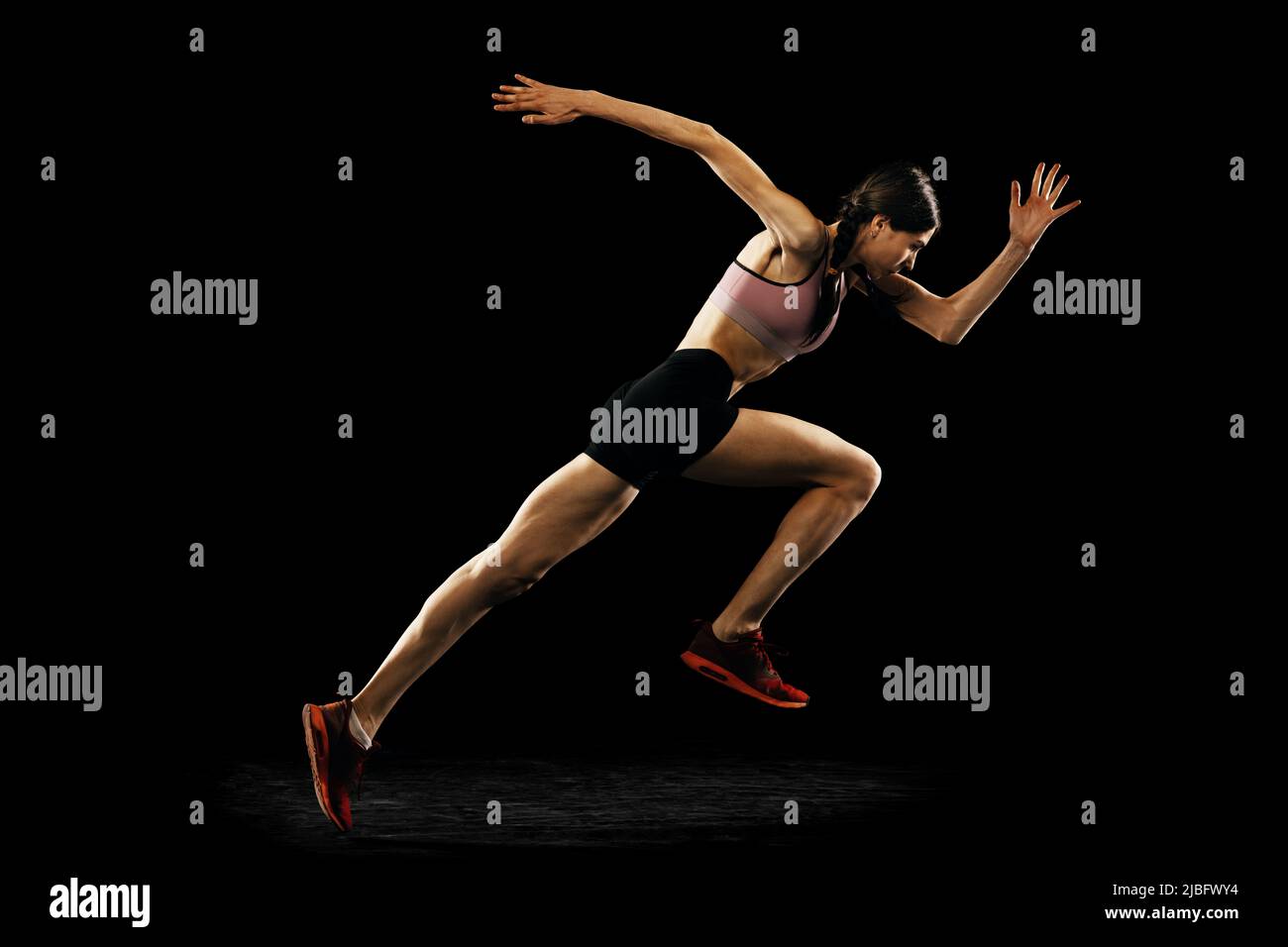 Studio shot of young muscular woman running isolated on black ...