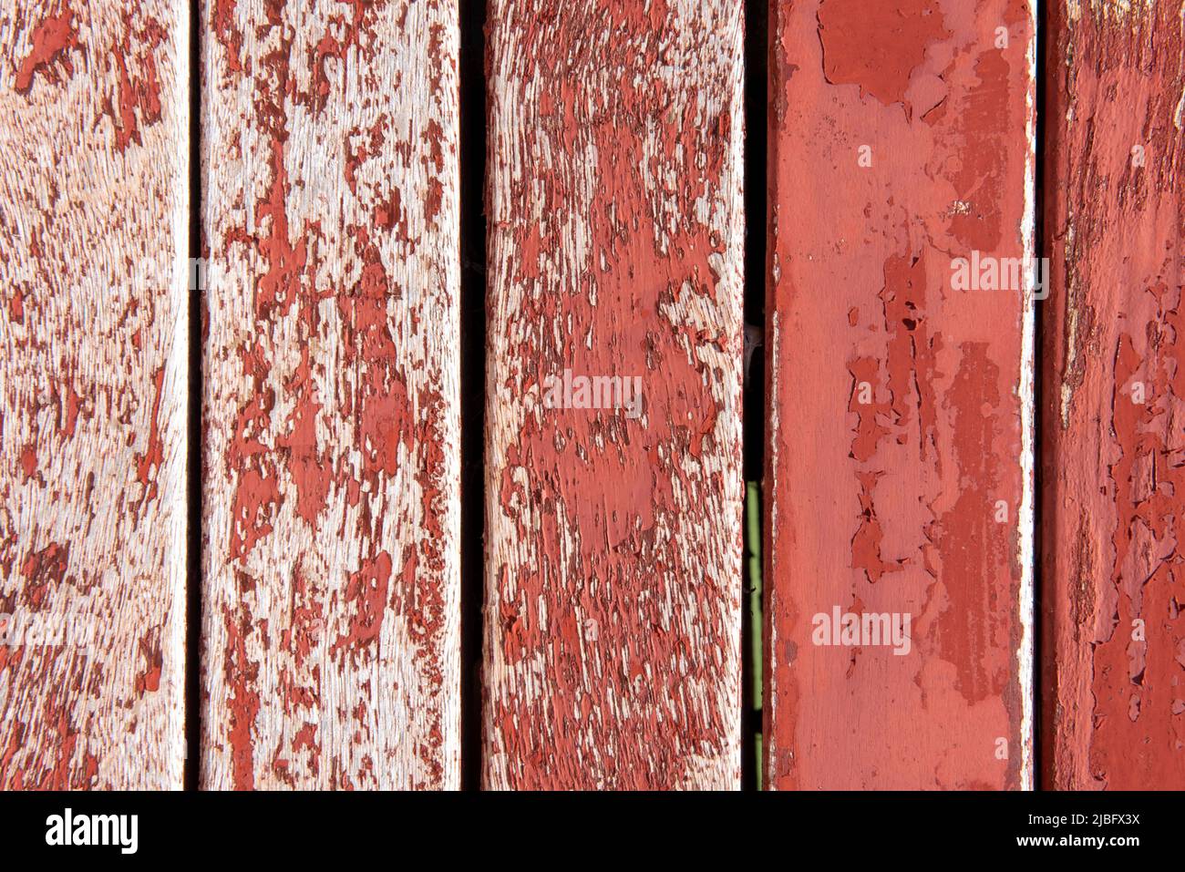 Red painted wooden boards in vertical position and peeled bottom ...