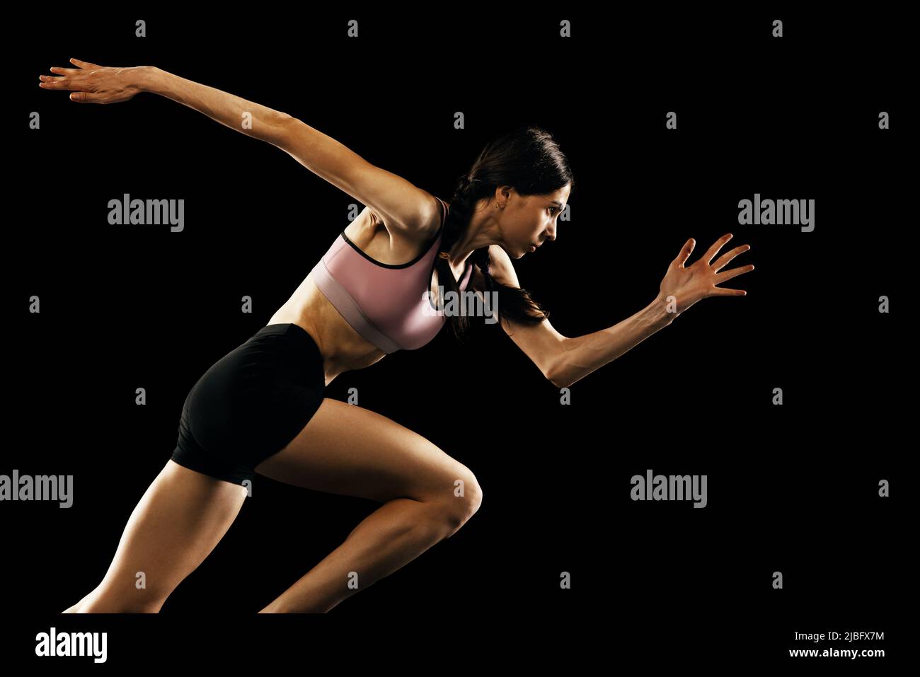 Studio shot of young muscular woman running isolated on black ...
