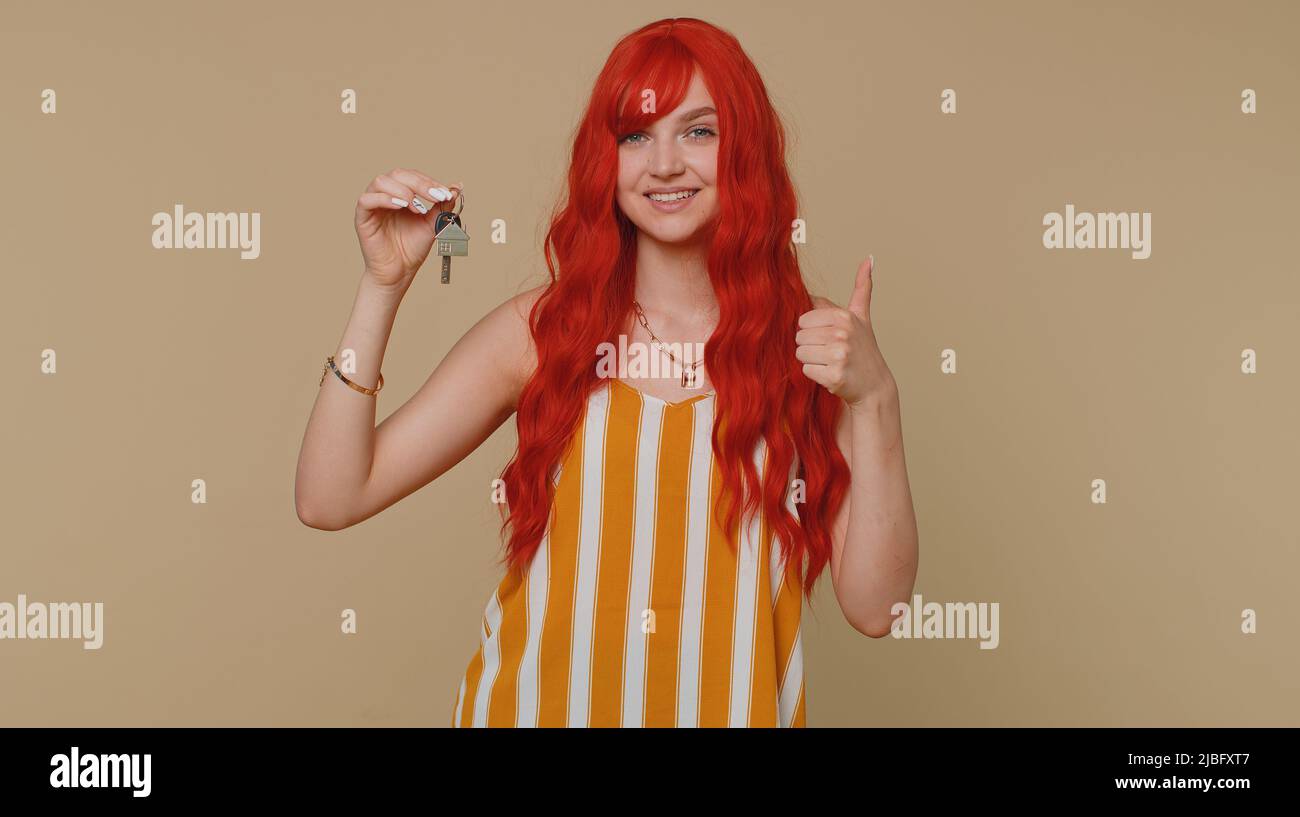 Redhead young woman real estate agent lifting hand showing the keys of ...