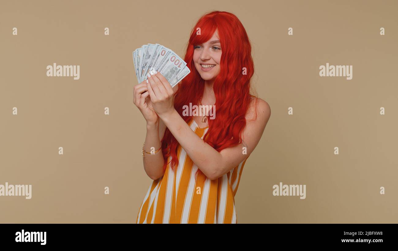 Redhead young woman holding fan of cash money dollar banknotes ...