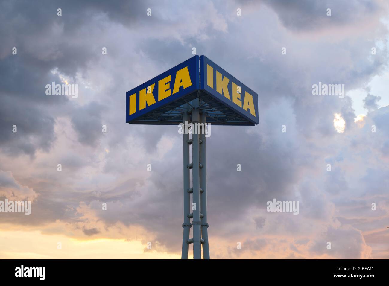 IKEA logo sign on a pole, against colorful sunset clouds. IKEA is a ...