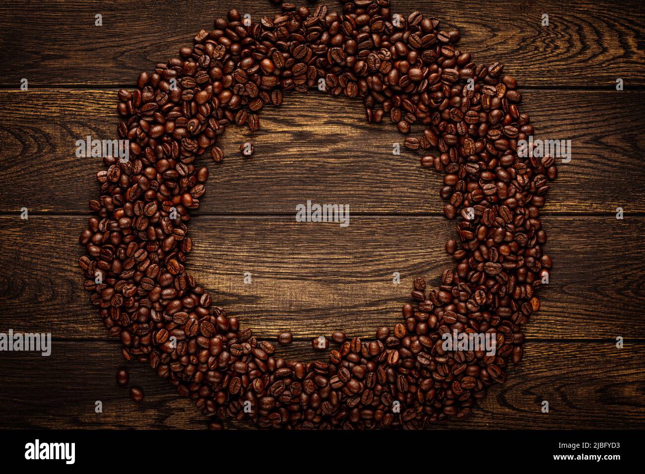 Roasted coffee beans arranged into ring. Brown grains scattered in ...